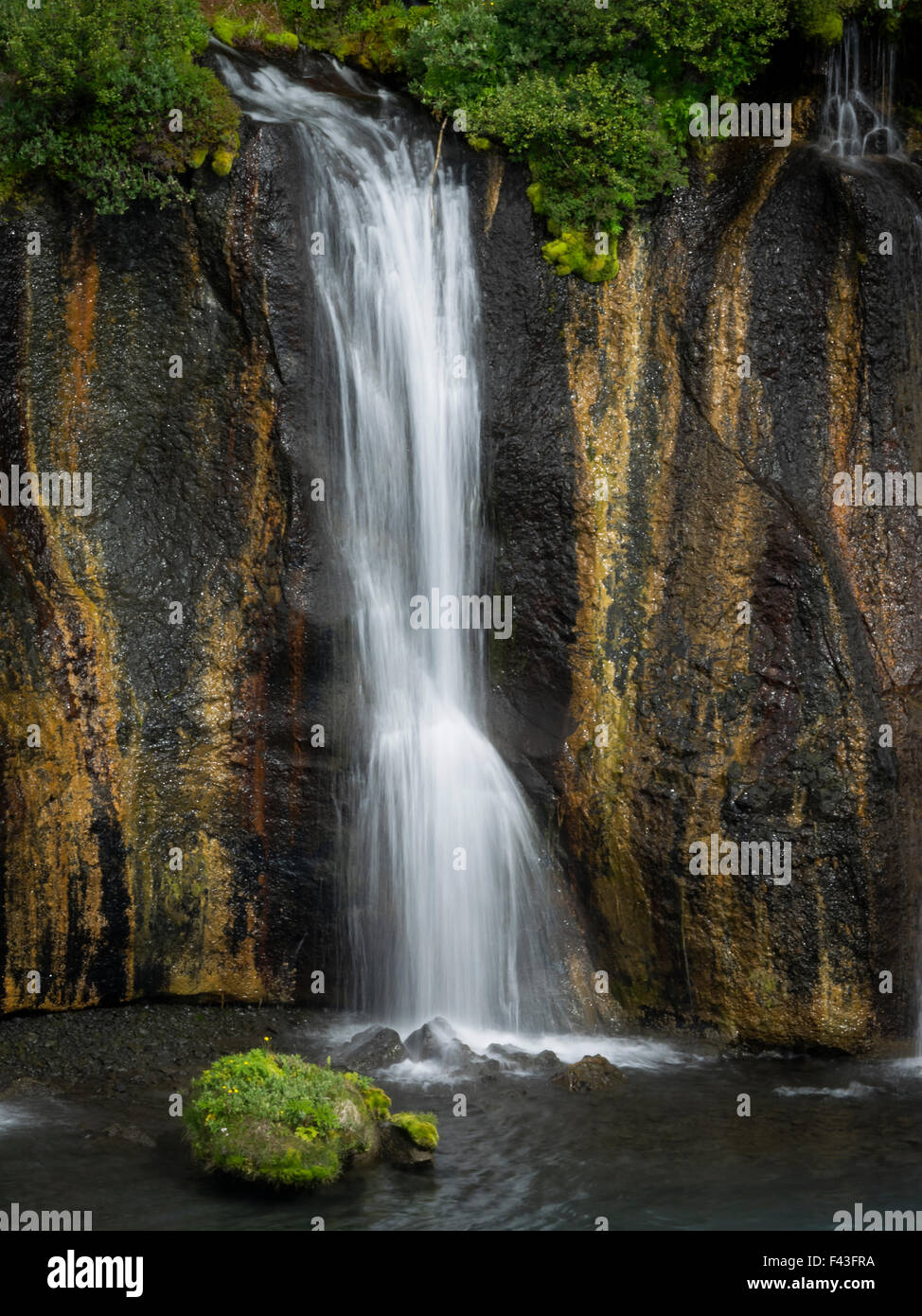 Hraunfossar waterfalls, a cascade of water over a sheer cliff into a ...
