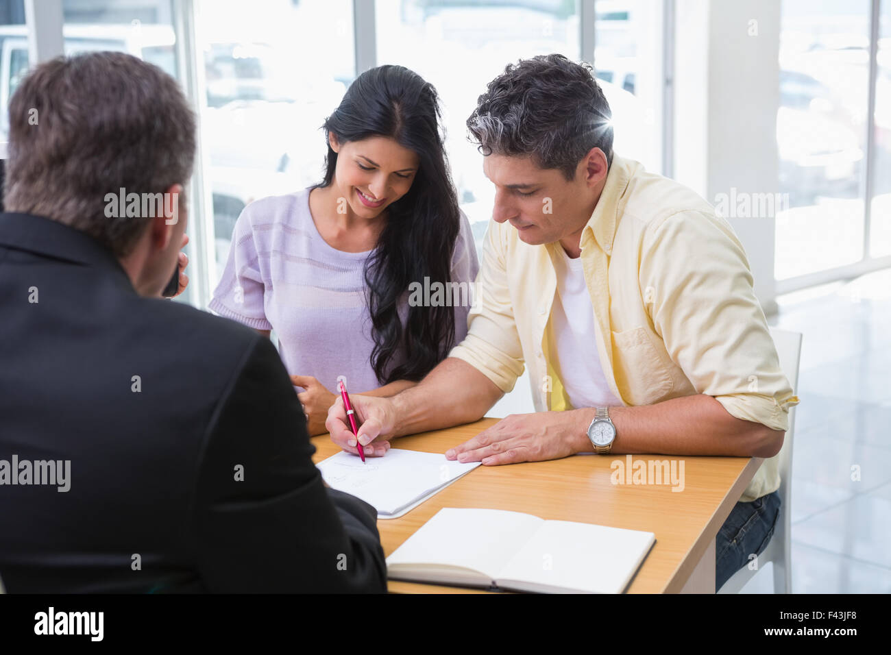Smiling couple signing a contract Stock Photo - Alamy