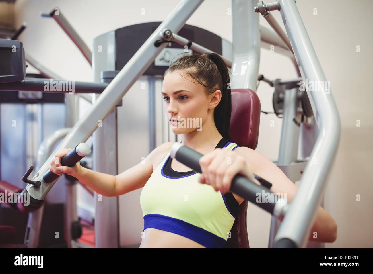 Fit woman using weights machine for arms Stock Photo - Alamy