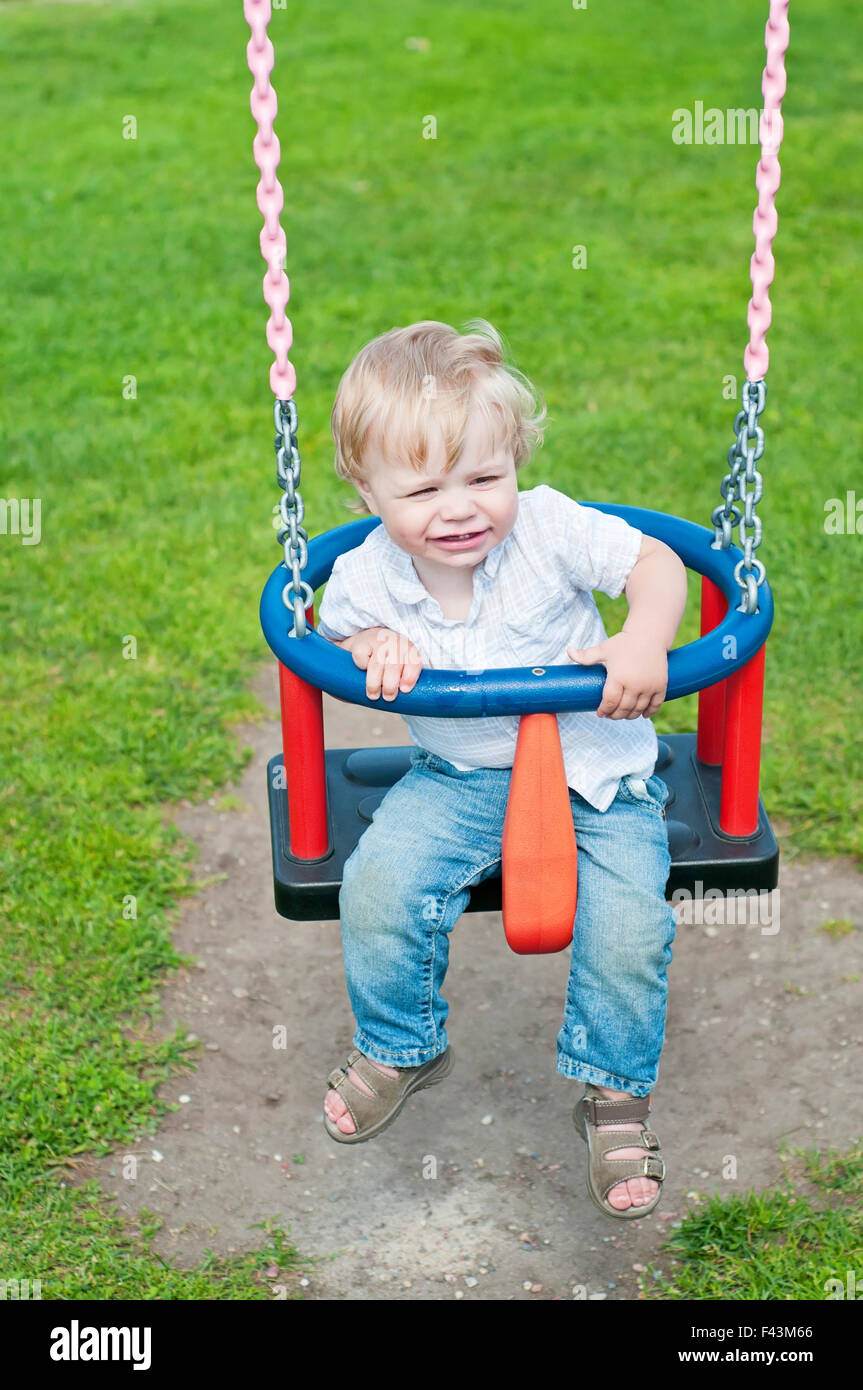 Cute baby boy playing on swing Stock Photo - Alamy