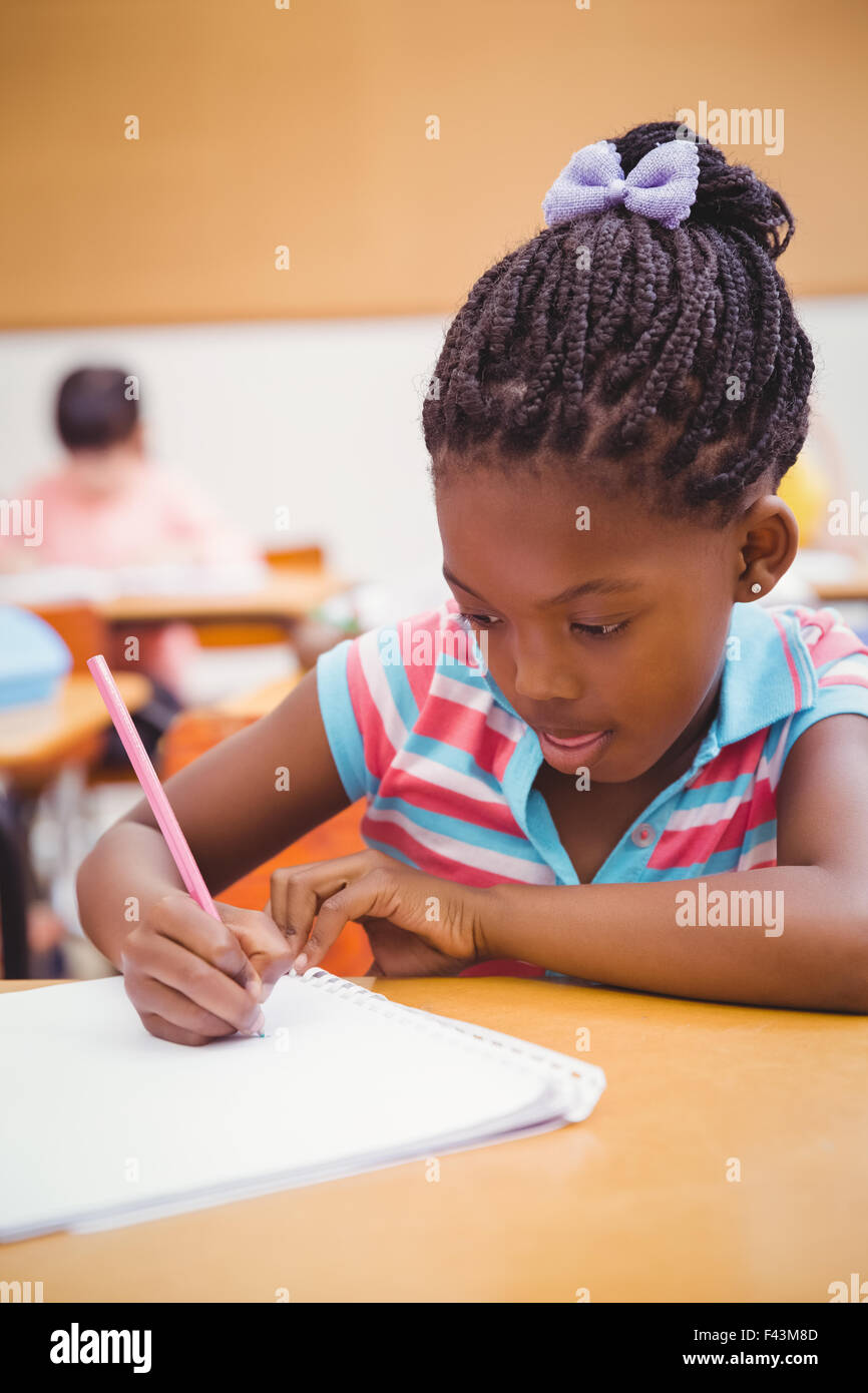 Cute pupils writing at desk in classroom Stock Photo - Alamy
