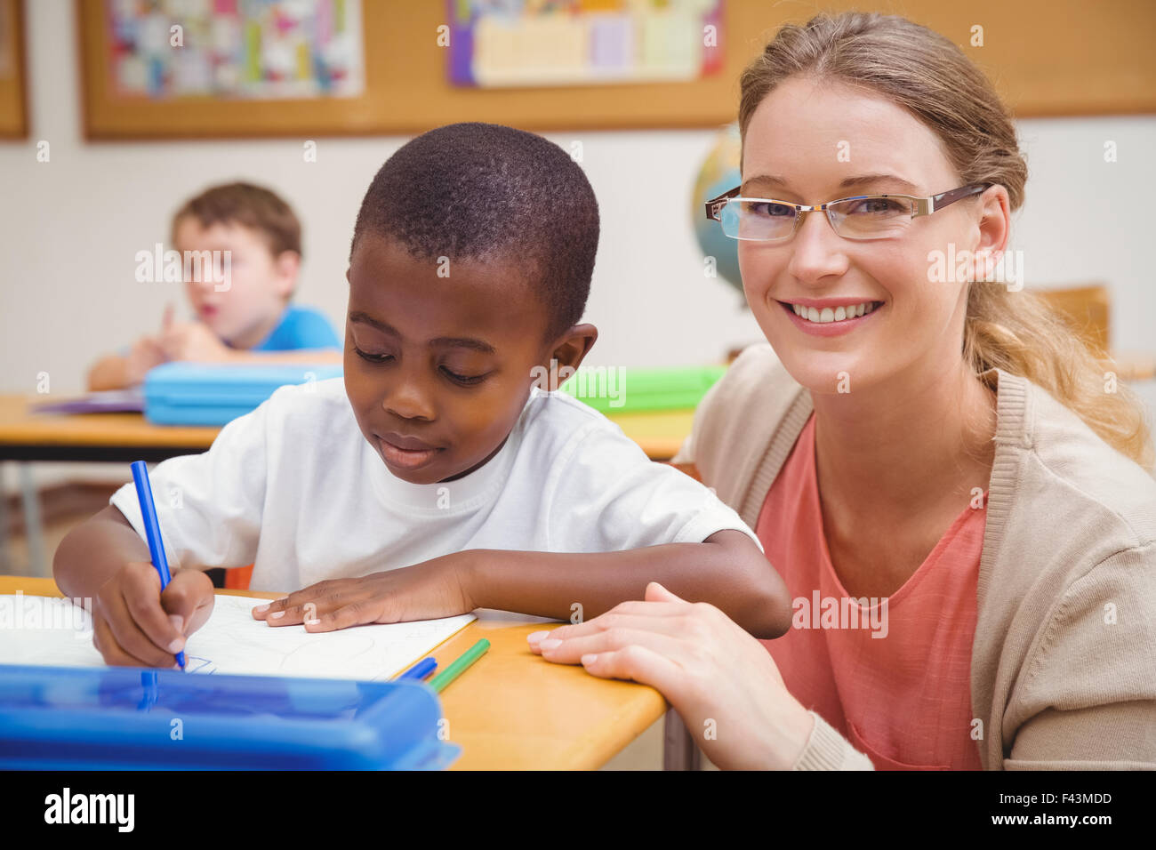 Pretty teacher helping pupil in classroom Stock Photo - Alamy
