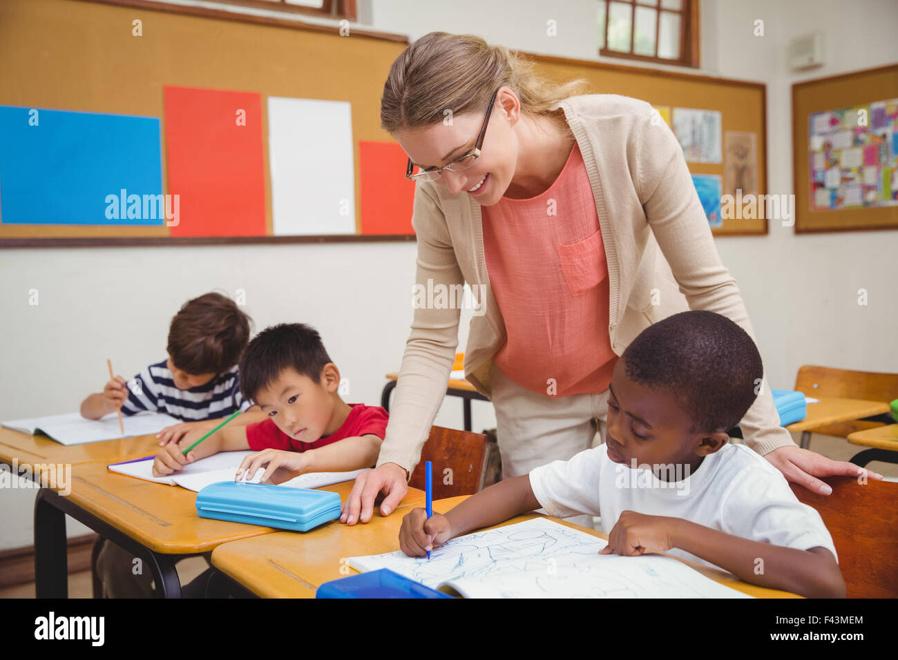 Pretty teacher helping pupil in classroom Stock Photo - Alamy
