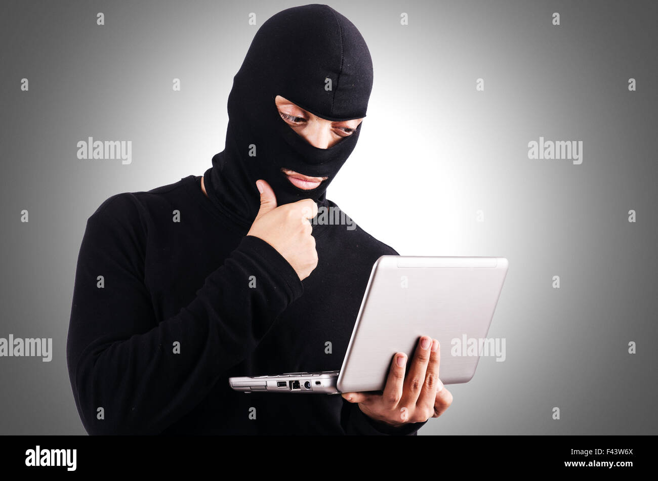 Hacker with computer wearing balaclava Stock Photo - Alamy
