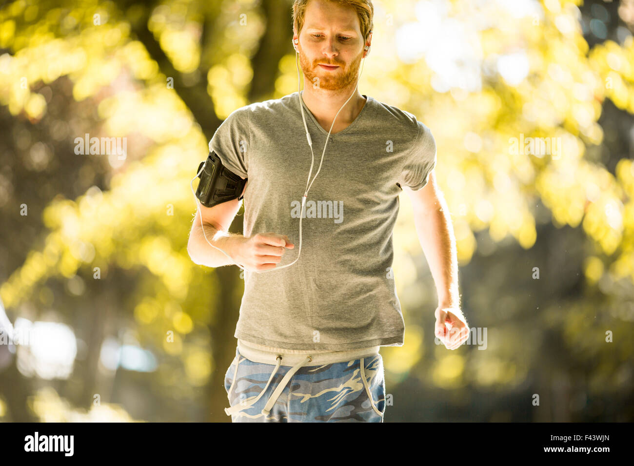 Young man running in the autumn park Stock Photo - Alamy