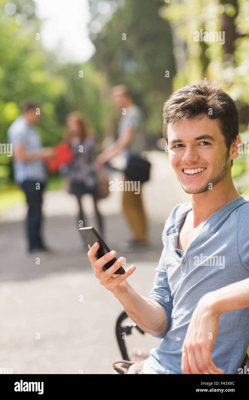 Handsome student sending a text outside Stock Photo - Alamy