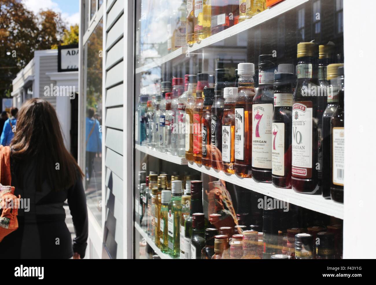 People walking by a storefront display of alcohol Stock Photo - Alamy