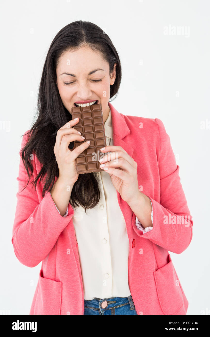 Smiling brunette biting bar of chocolate Stock Photo - Alamy