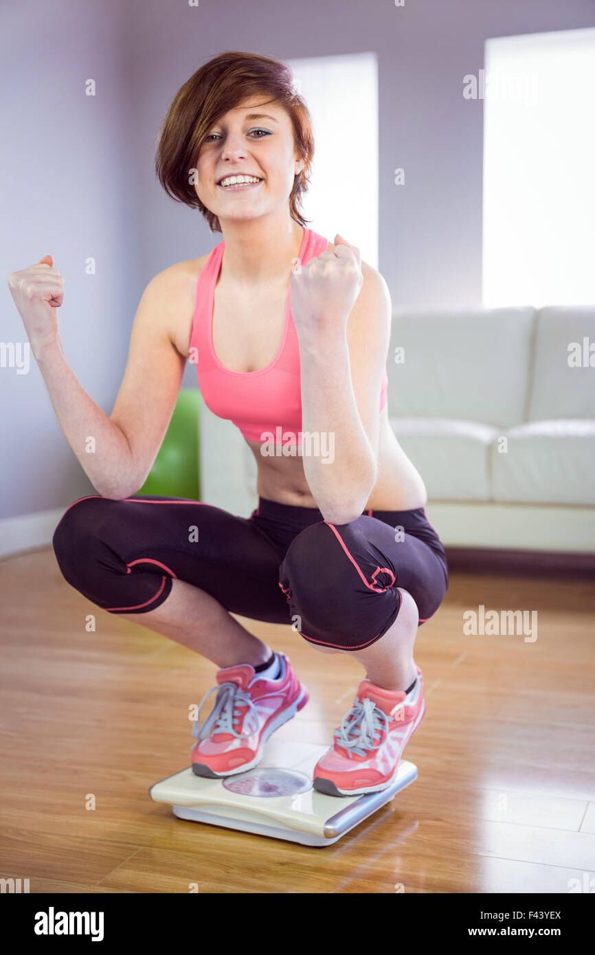 Slim woman cheering on scales Stock Photo - Alamy