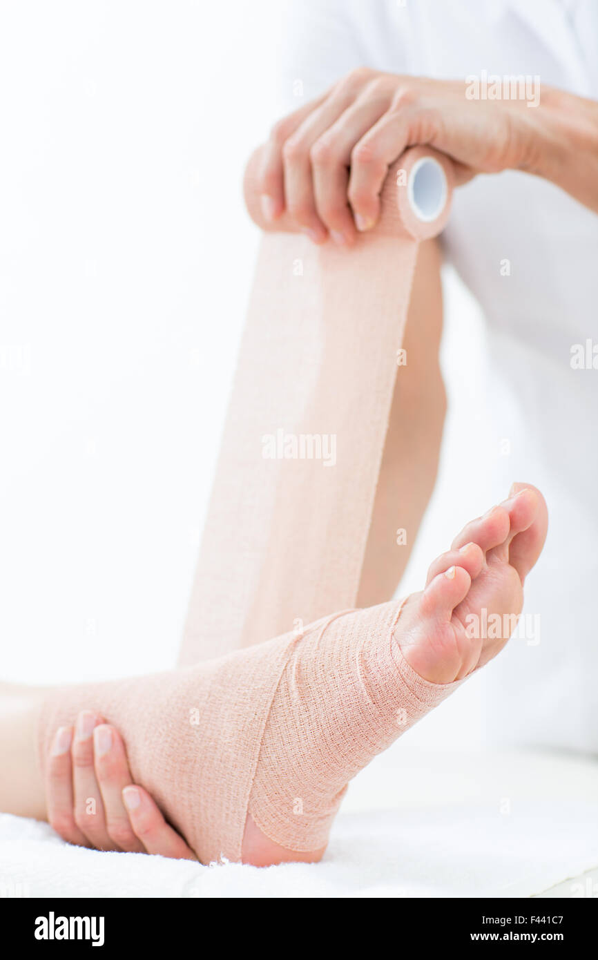 Doctor bandaging her patient ankle Stock Photo - Alamy