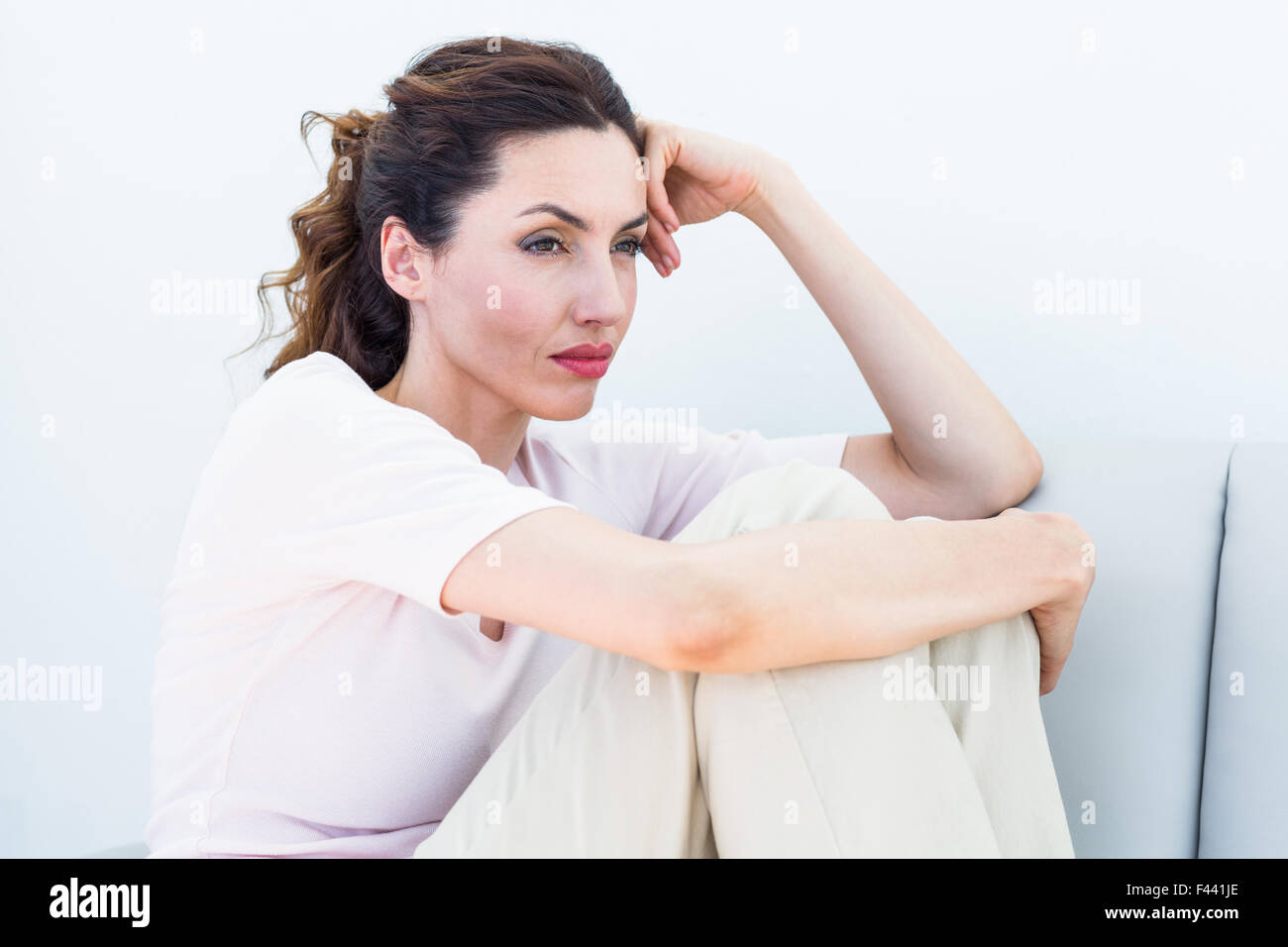 Sad brunette sitting on the couch Stock Photo - Alamy