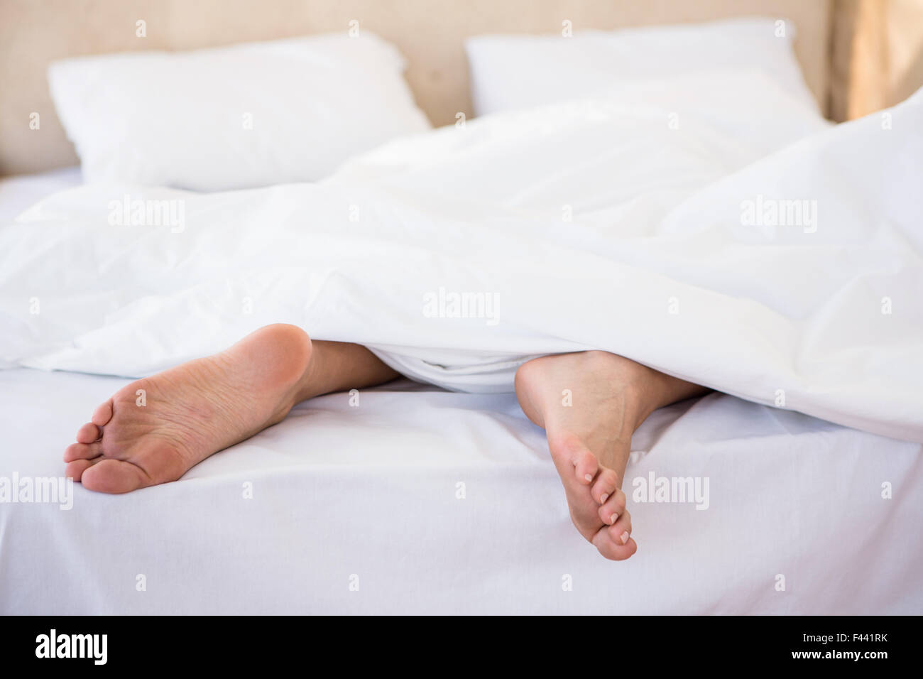 Woman feet under a duvet Stock Photo - Alamy