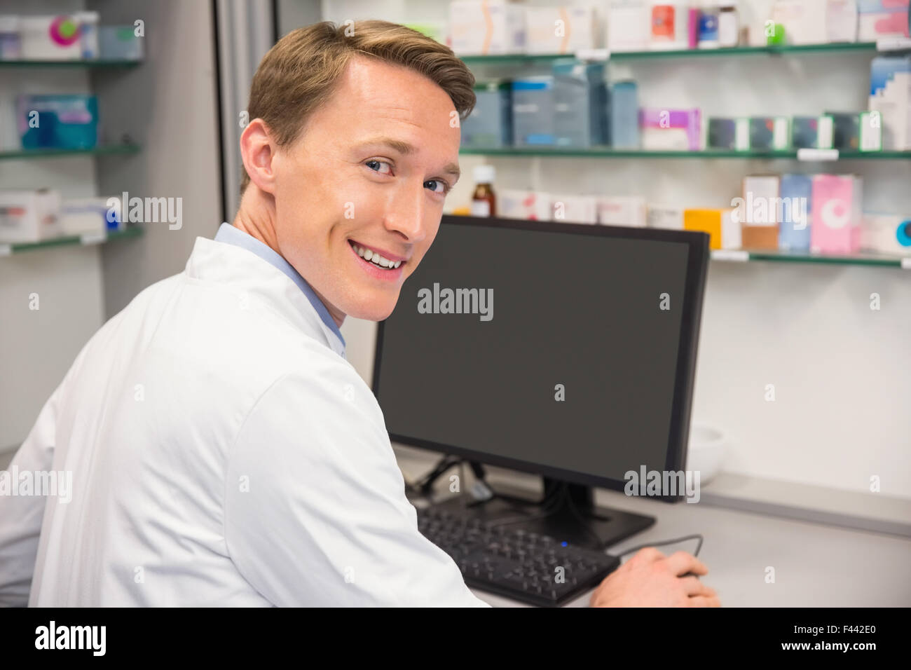 Happy pharmacist using the computer Stock Photo - Alamy