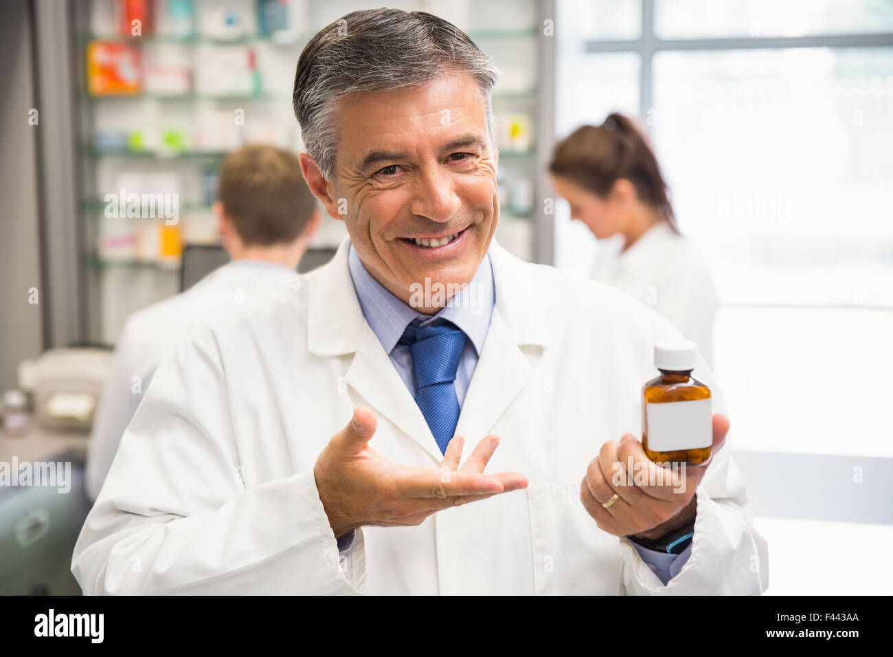 Senior pharmacist showing medicine jar Stock Photo - Alamy