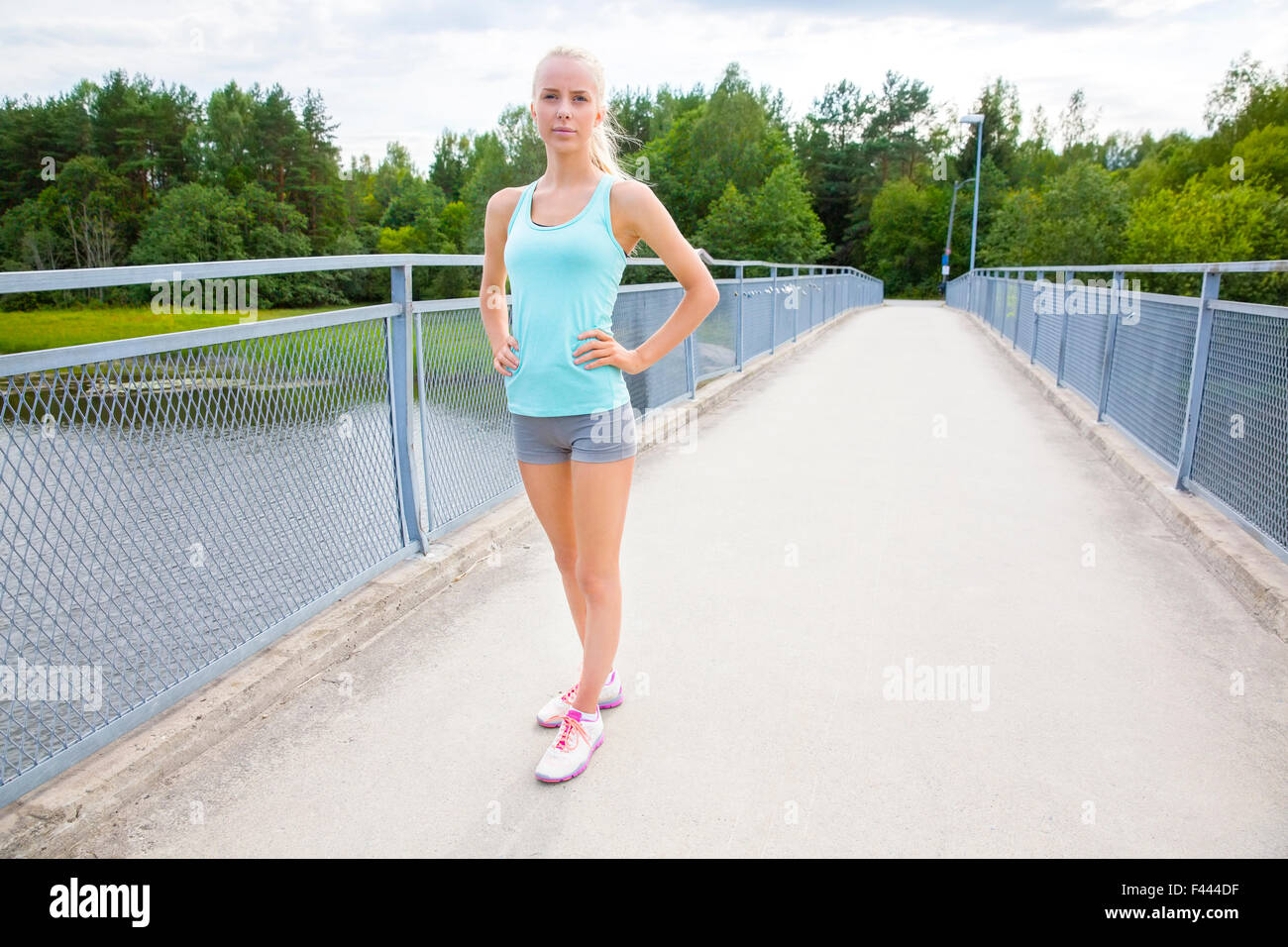 Beautiful and confident young female runner stands at bridge Stock ...
