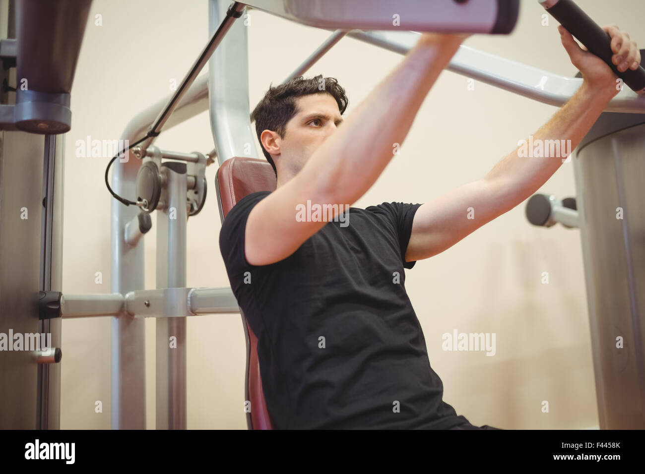 Fit man using weights machine for arms Stock Photo - Alamy