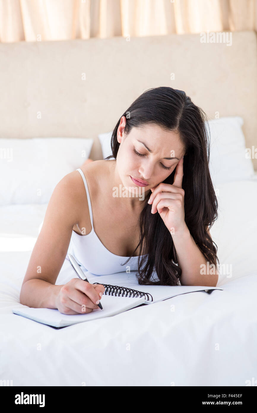 Pretty brunette writing on bed Stock Photo - Alamy