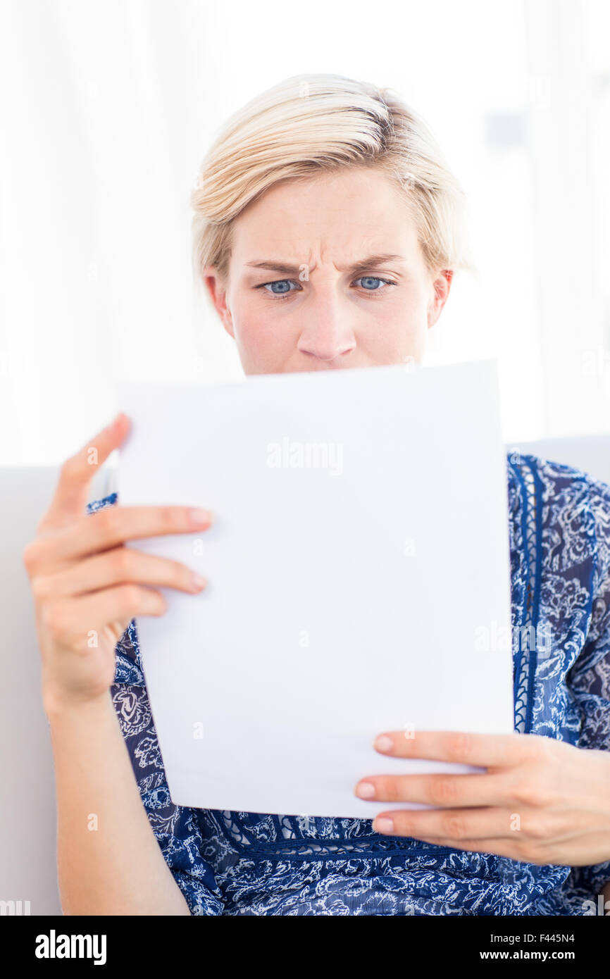 Worried blonde woman reading a paper Stock Photo - Alamy