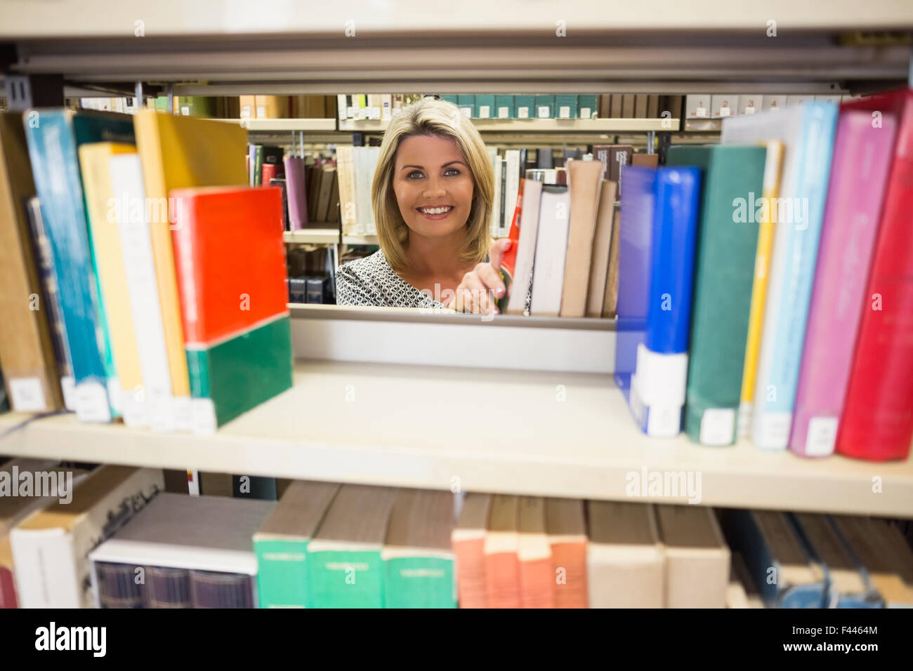 Mature student taking a book in library Stock Photo - Alamy