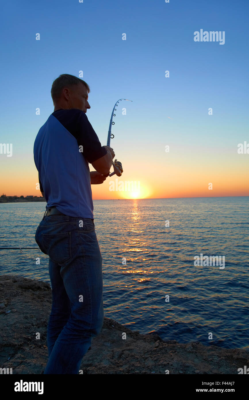 Fisherman fishes at the sunset Stock Photo - Alamy