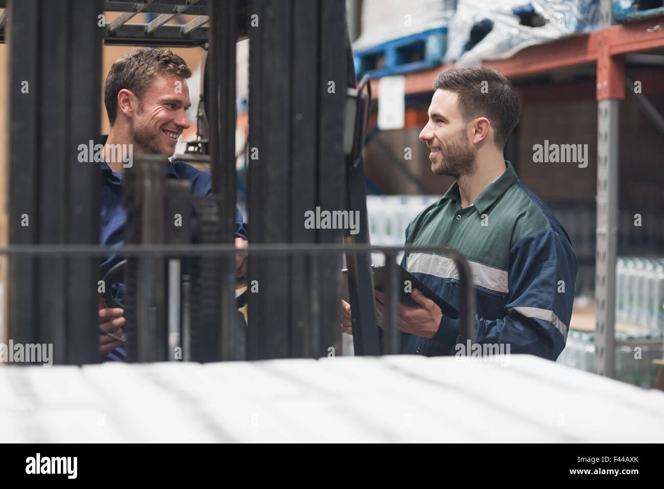Smiling warehouse workers talking together Stock Photo - Alamy