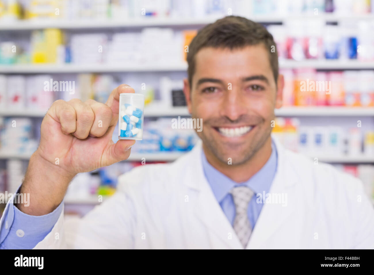 Handsome pharmacist showing medicine jar Stock Photo - Alamy