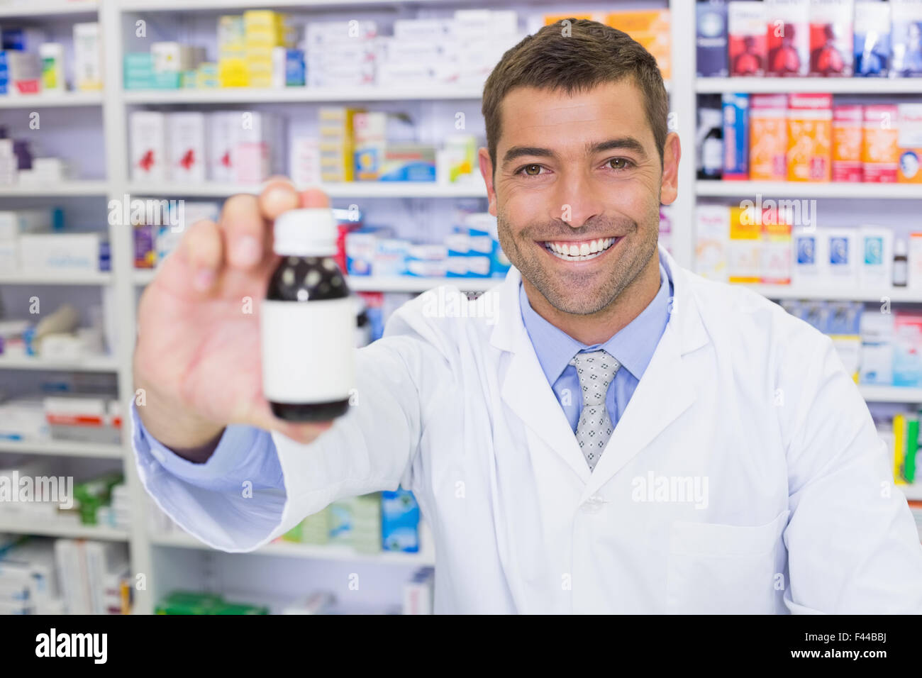Handsome pharmacist showing medicine bottle Stock Photo - Alamy
