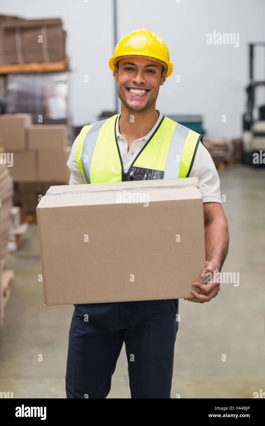 Worker carrying box in warehouse Stock Photo - Alamy