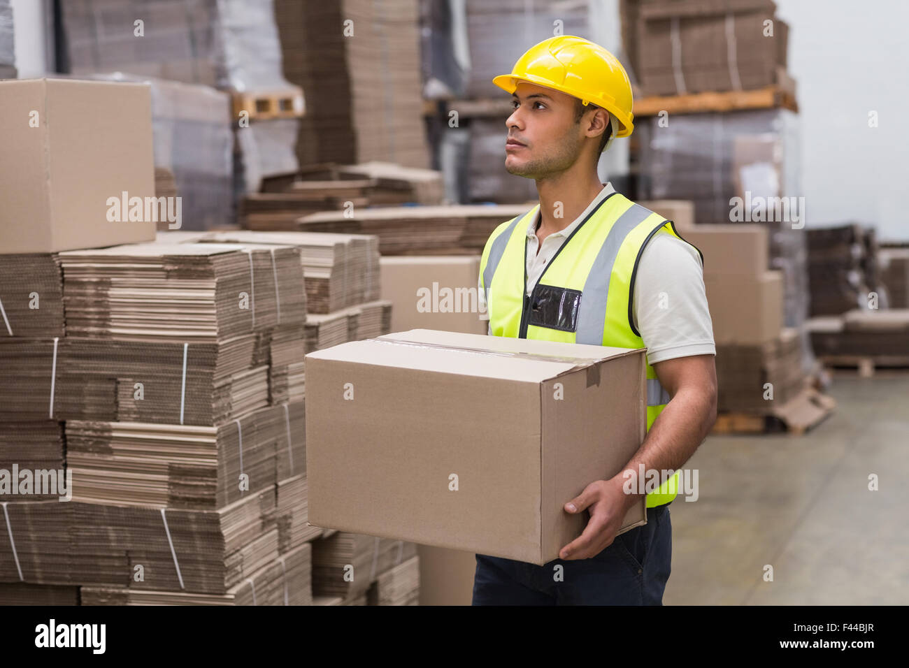 Worker carrying box in warehouse Stock Photo - Alamy