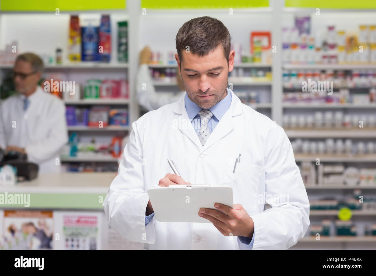Pharmacist writing on clipboard Stock Photo - Alamy