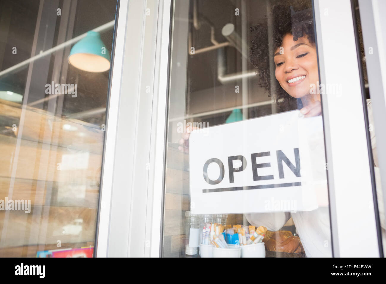 Pretty worker presenting open sign Stock Photo - Alamy