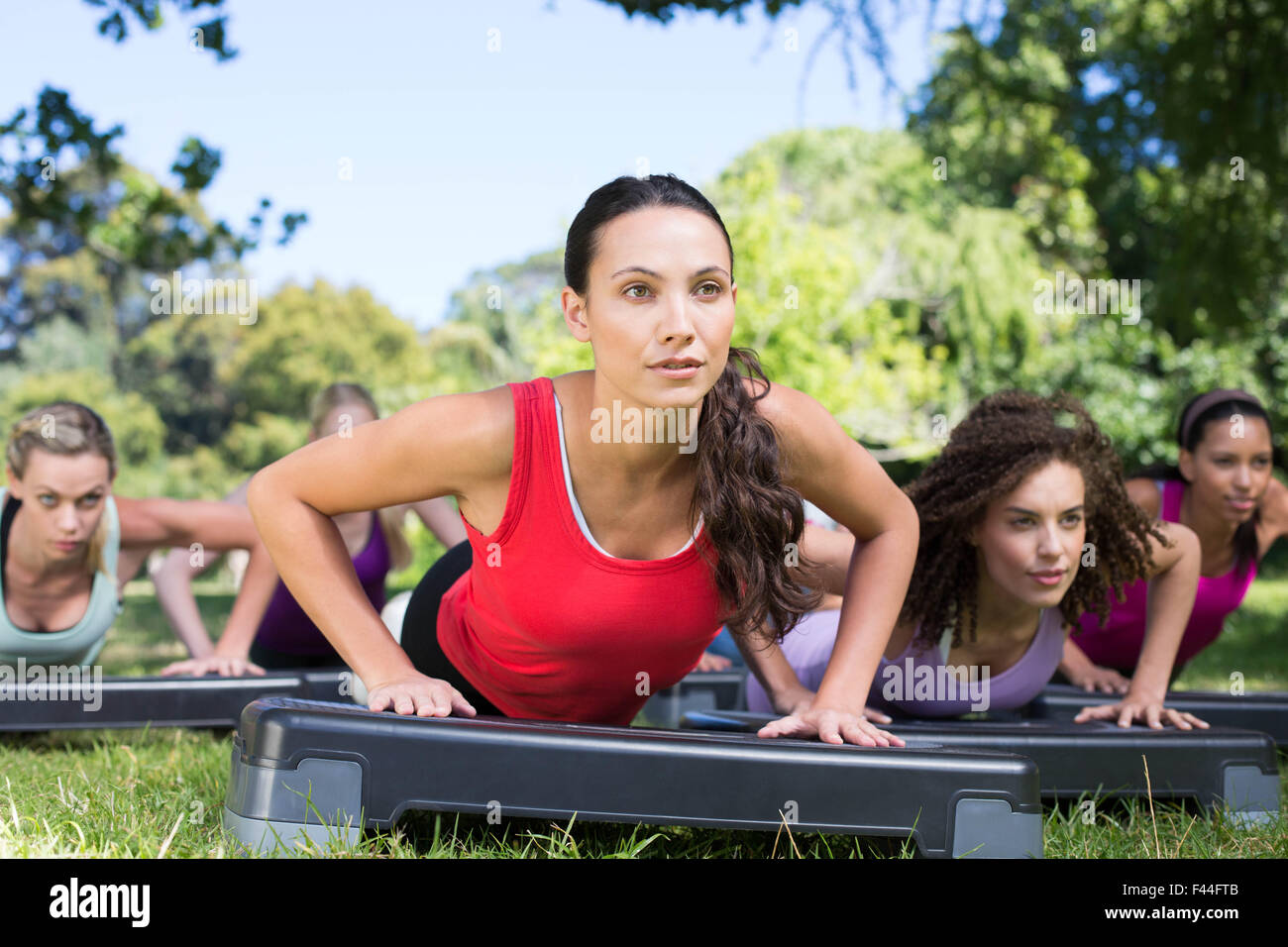 Fitness group using steps in park Stock Photo - Alamy