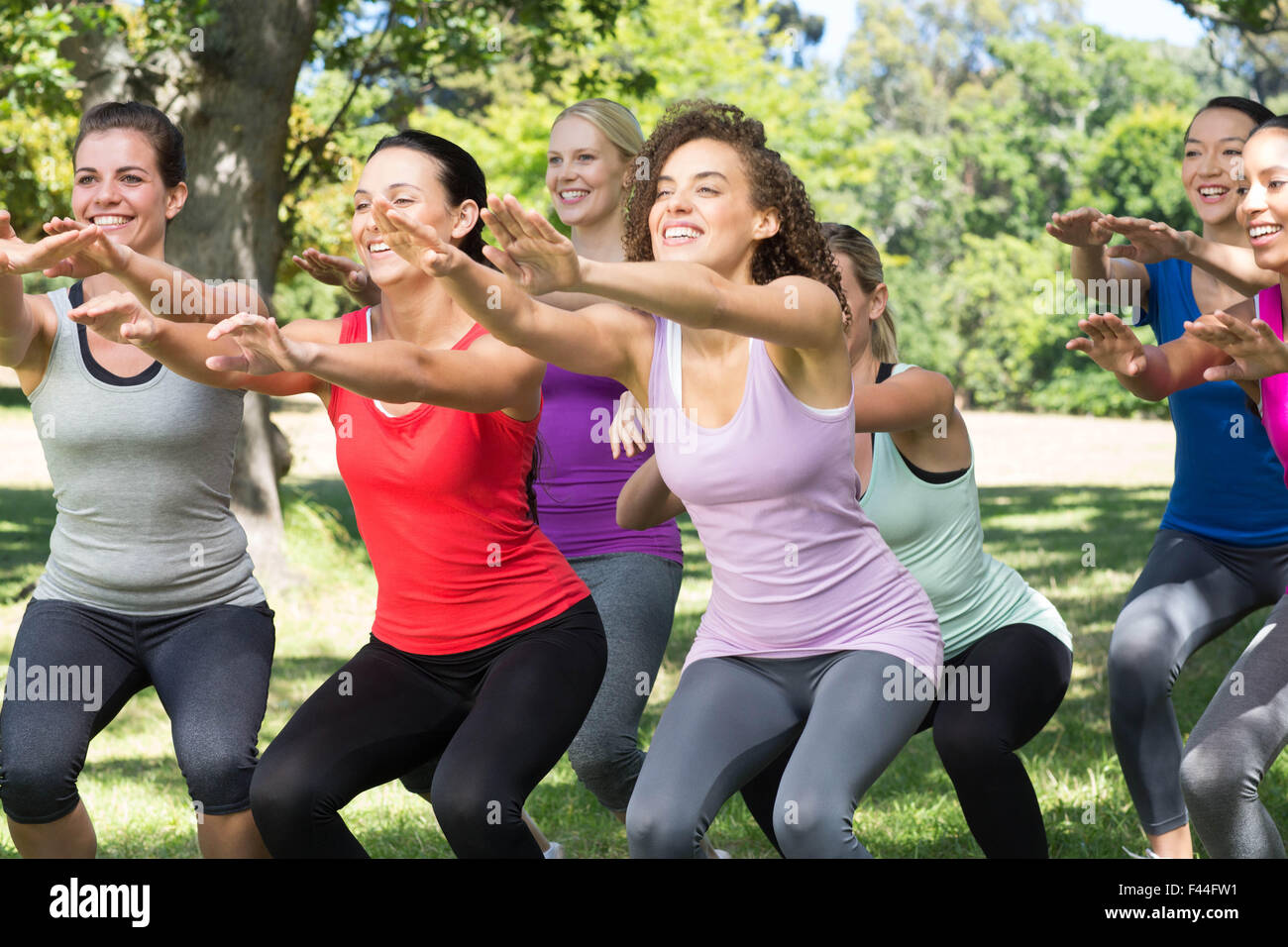 Fitness group squatting in park Stock Photo - Alamy