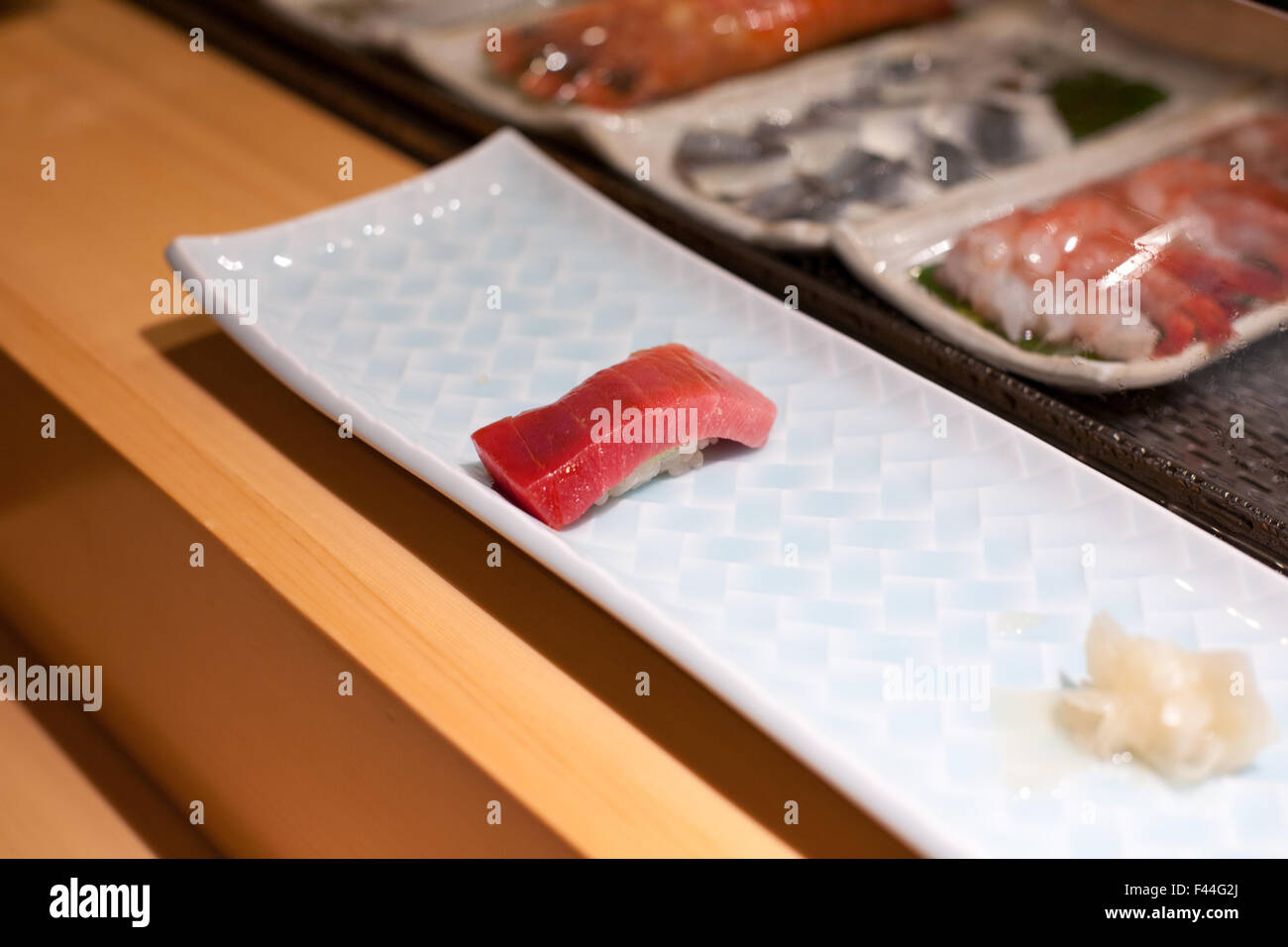 Fatty tuna chu toro sushi on plate with ginger glass case behind depth ...