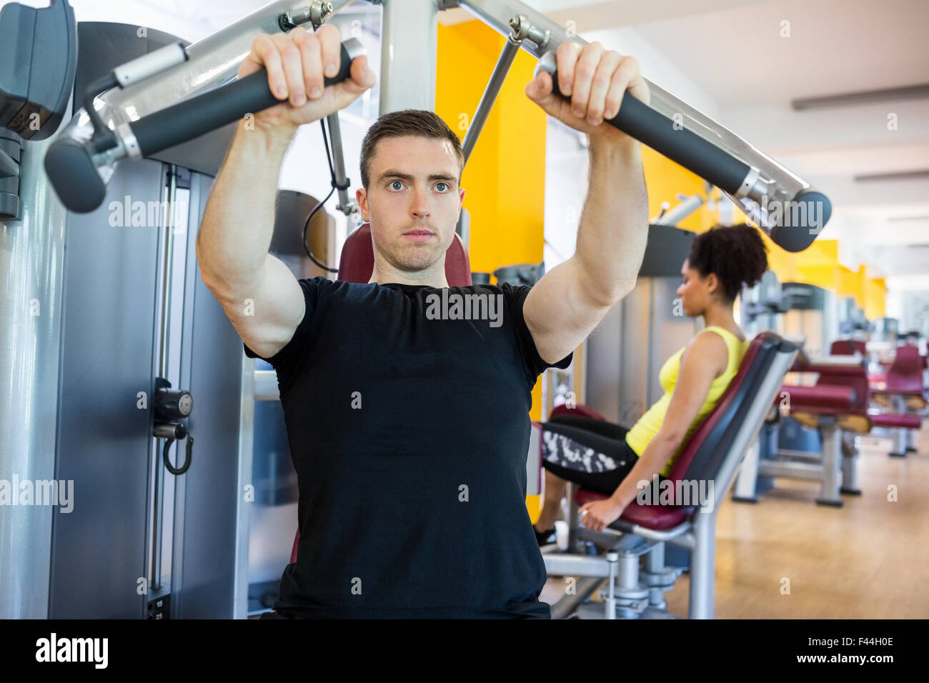 Fit man using weights machine for arms Stock Photo - Alamy