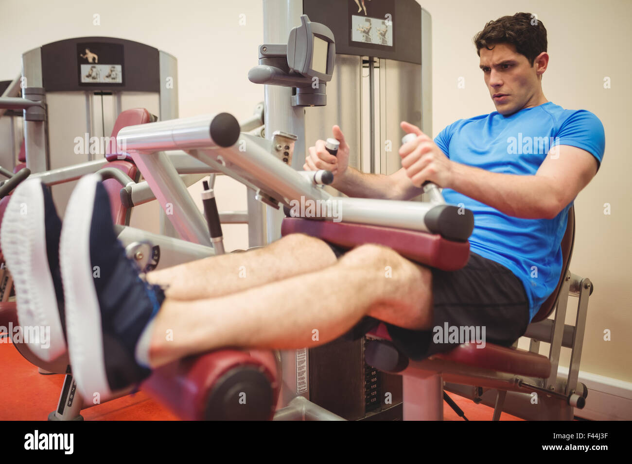 Fit man using weights machine for legs Stock Photo - Alamy