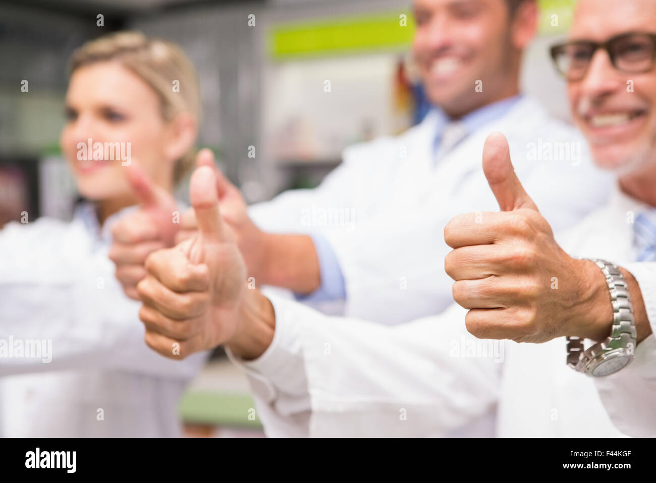 Positive co-workers standing with thumbs up Stock Photo - Alamy