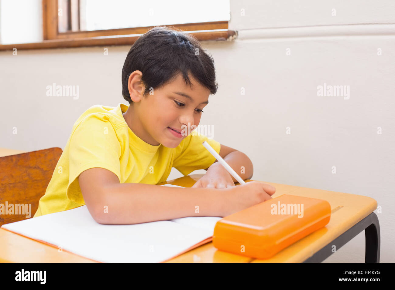 Cute pupil writing at desk in classroom Stock Photo - Alamy