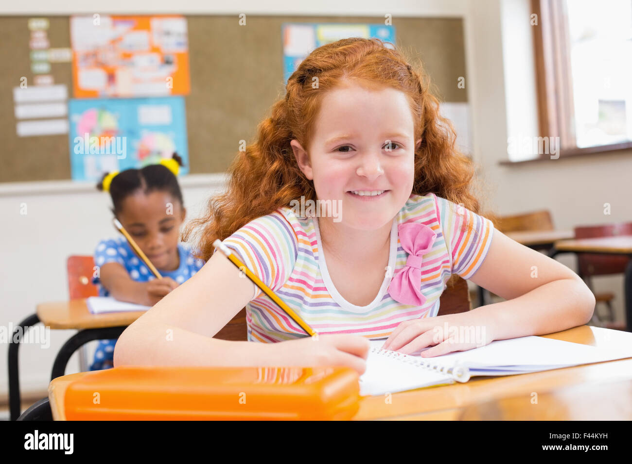Cute pupils writing at desk in classroom Stock Photo - Alamy