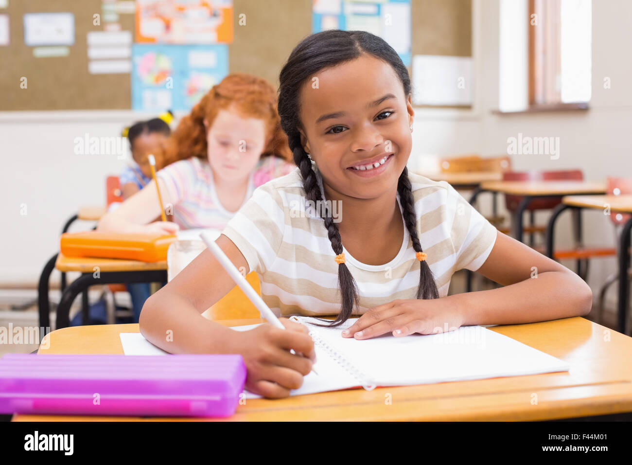 Cute pupils writing at desk in classroom Stock Photo - Alamy