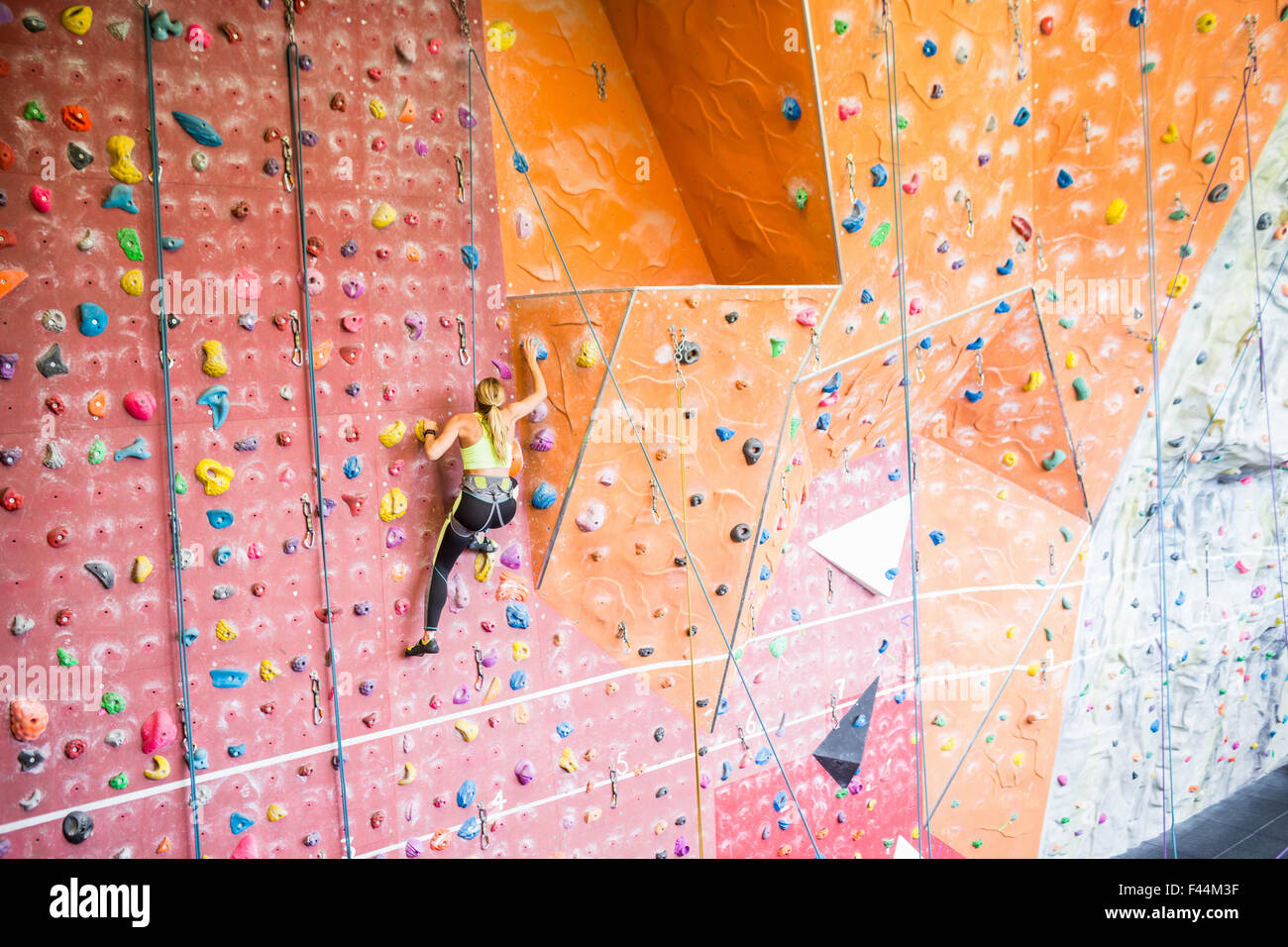 Fit woman rock climbing indoors Stock Photo - Alamy