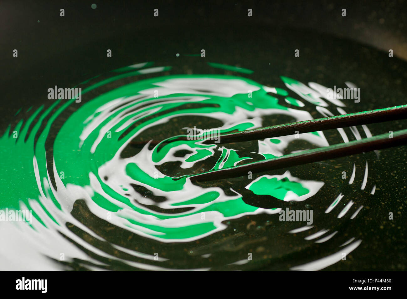 Water making ripples in water with chopsticks light color green and ...