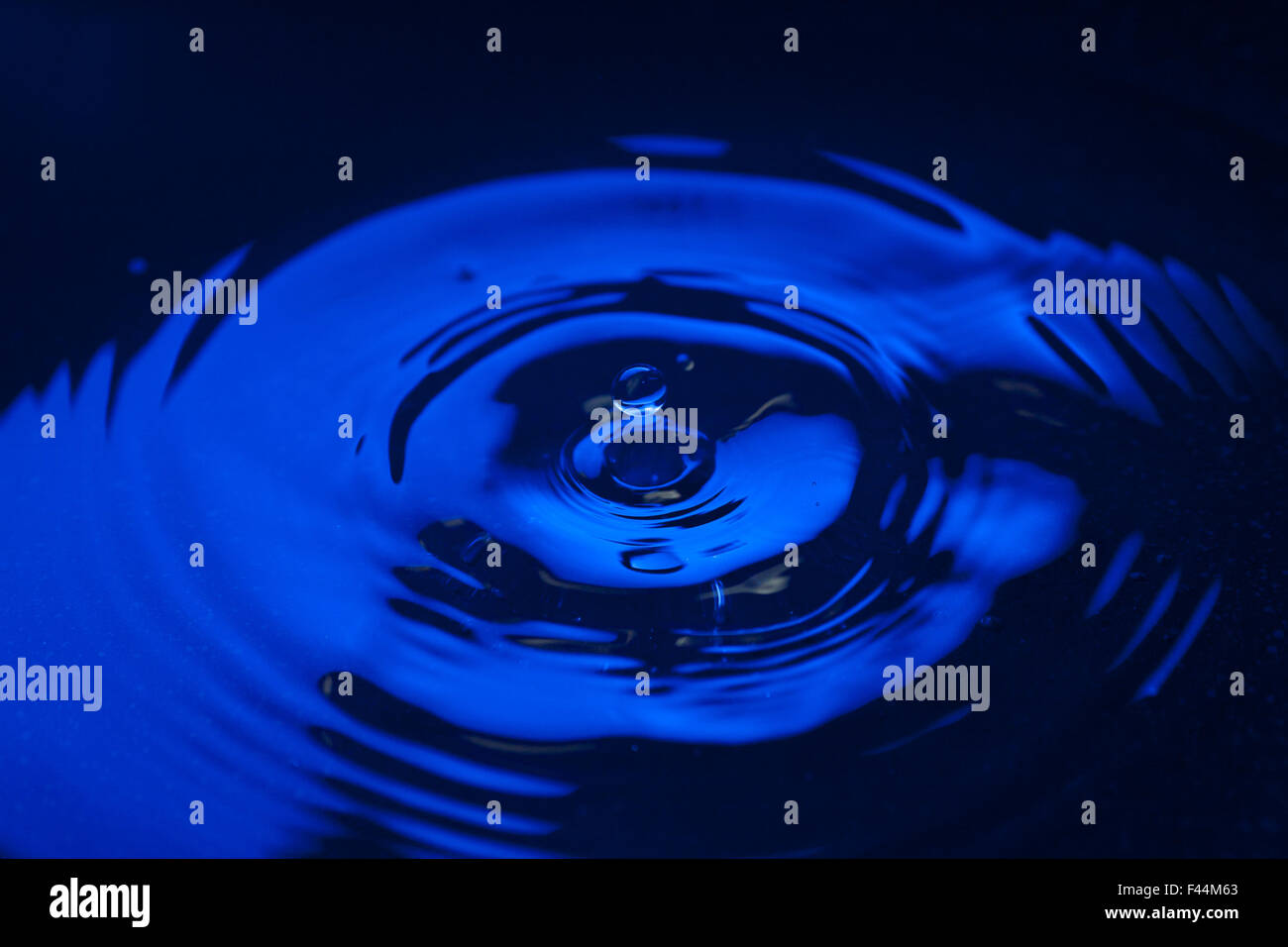 Water droplet making ripples in water blue dominant Stock Photo - Alamy