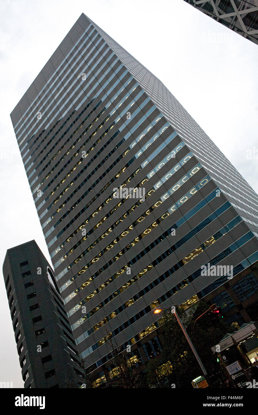 Glass and dark gray striped office building with trees below later ...