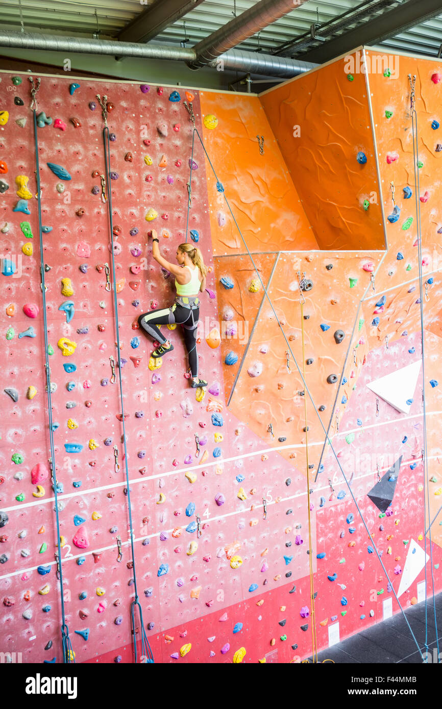 Fit woman rock climbing indoors Stock Photo - Alamy