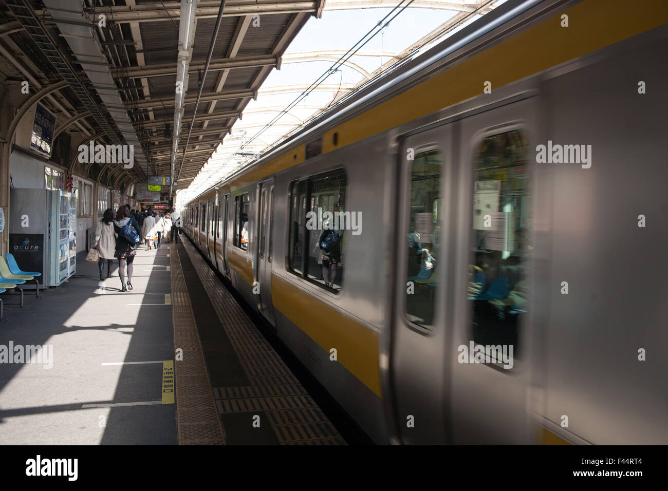 Train platform with yellow stripe train and people walking away Stock ...