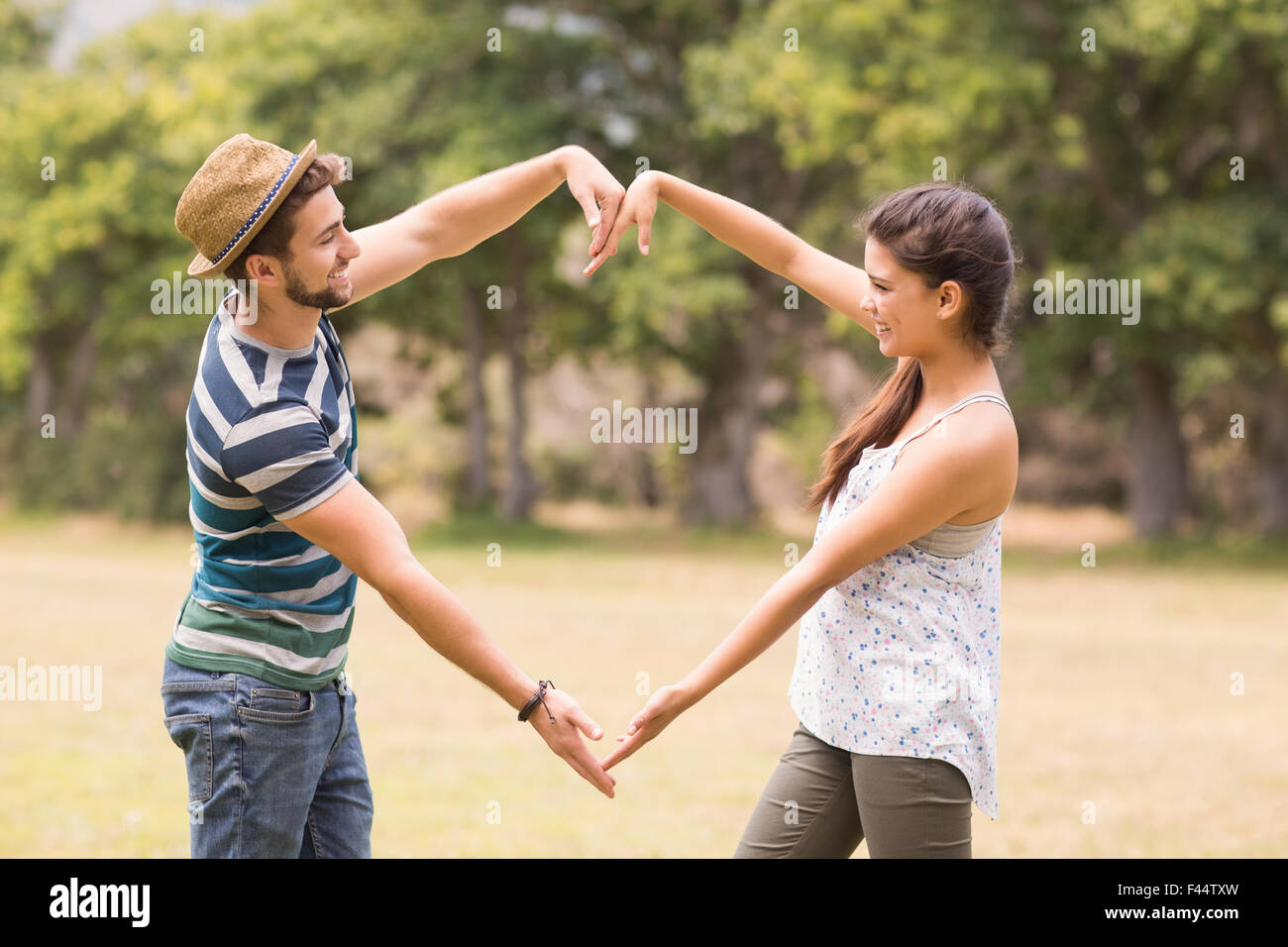 Cute couple in the park making heart shape Stock Photo - Alamy
