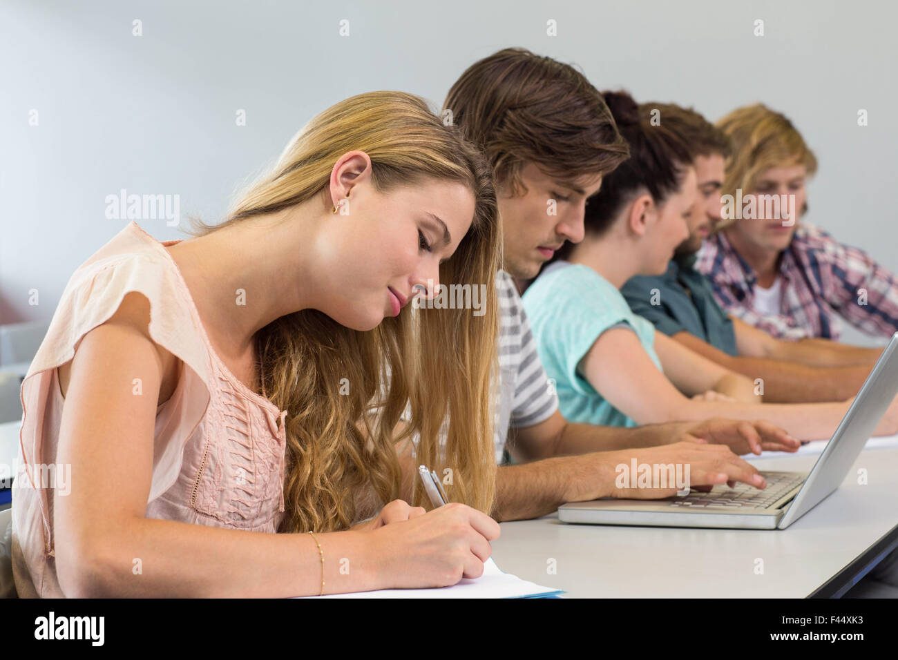 Students writing notes in classroom Stock Photo - Alamy
