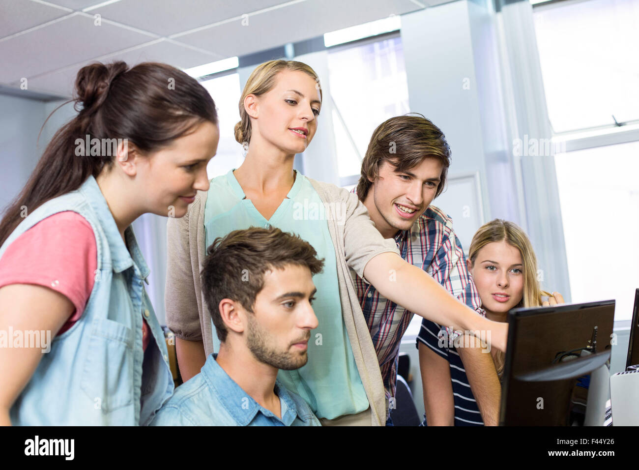 Teacher helping students in her class Stock Photo - Alamy