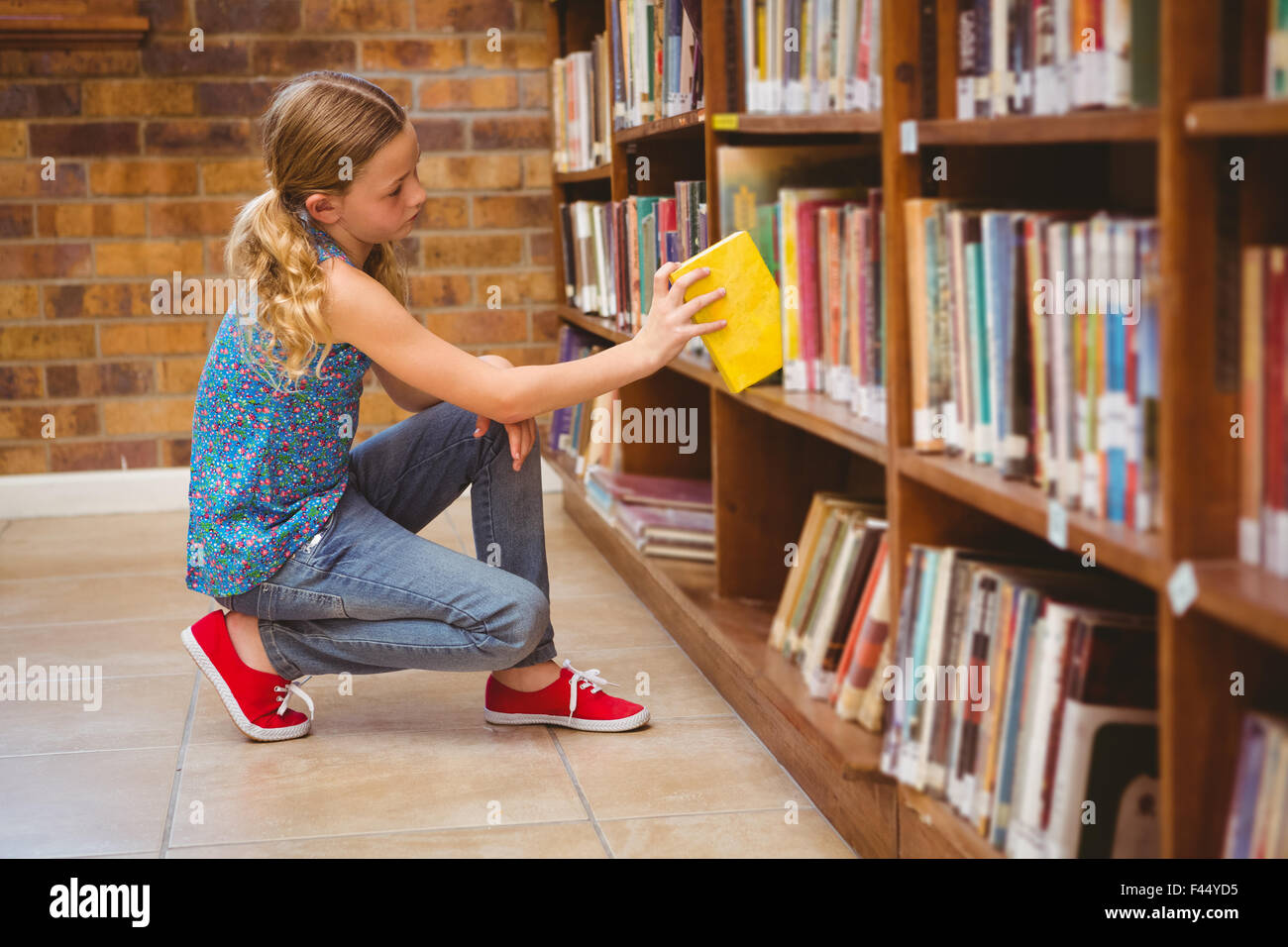 Cute little girl selecting book in library Stock Photo - Alamy